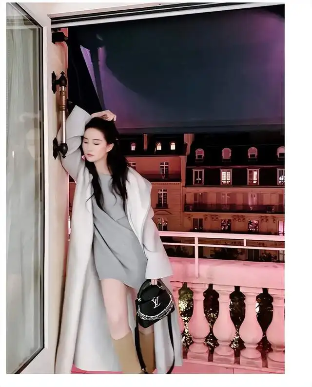 刘亦菲身穿浅灰大衣披散长发，倚靠门框拍照尽显慵懒